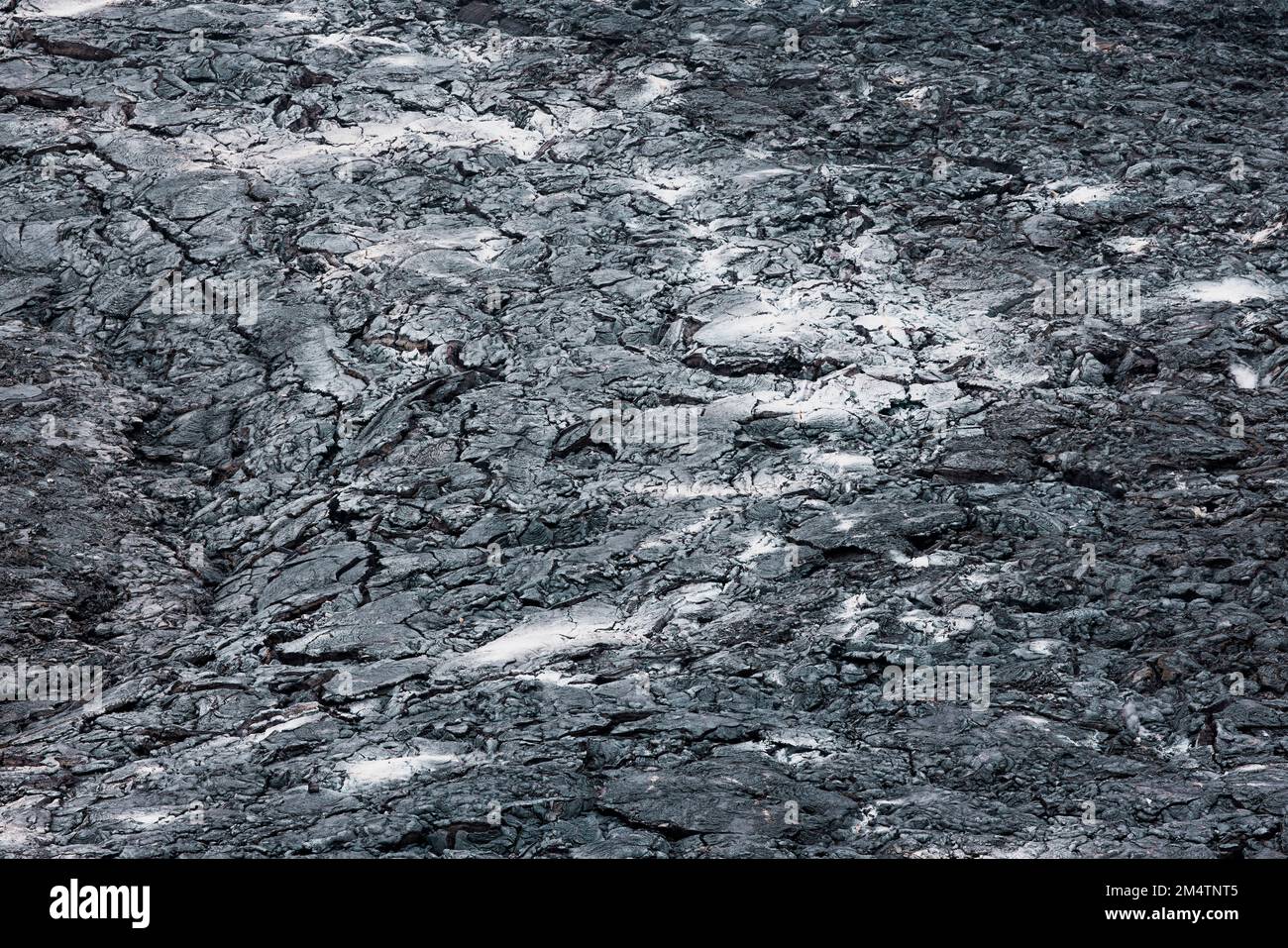 Close up cooled black volcanic rock, with ash grey patches on the ...