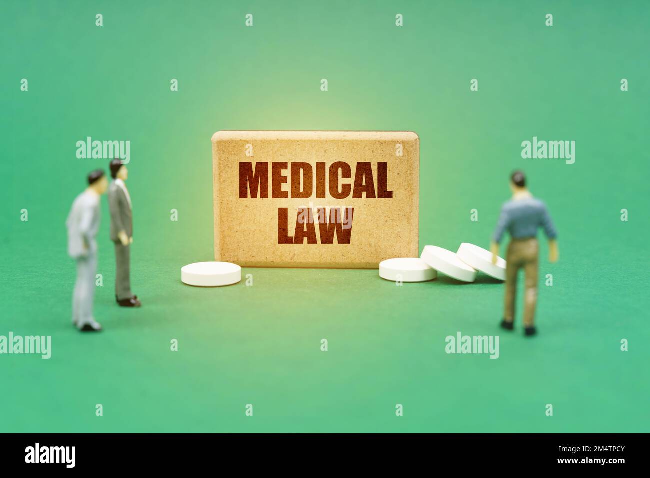 Medical concept. On the green surface are pills, miniature figures of ...