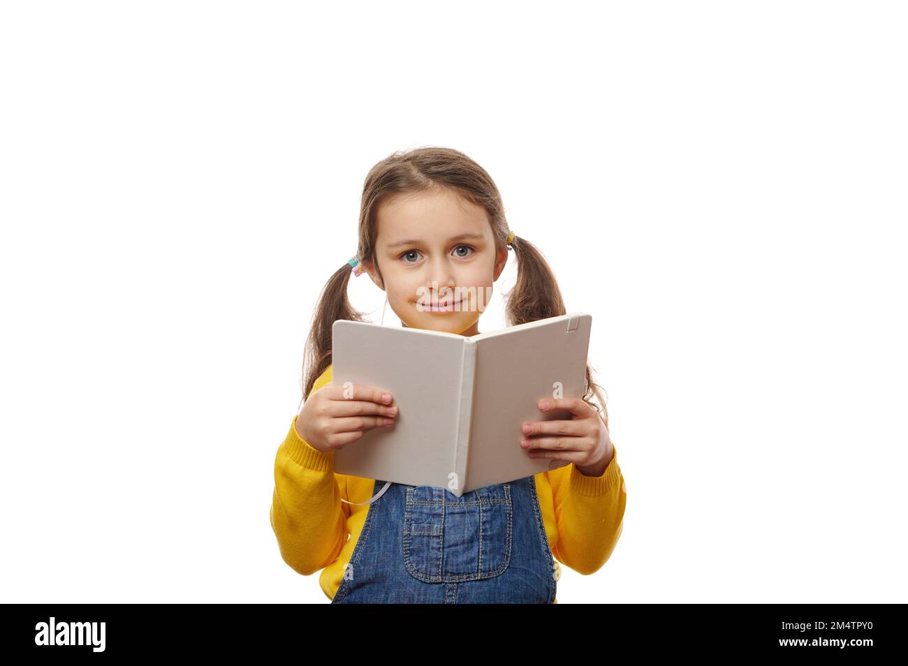 Smart first grade schoolgirl reading book over white background. Back ...