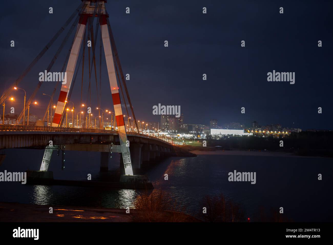 A large automobile bridge on which cars drive at night. A bridge with ...