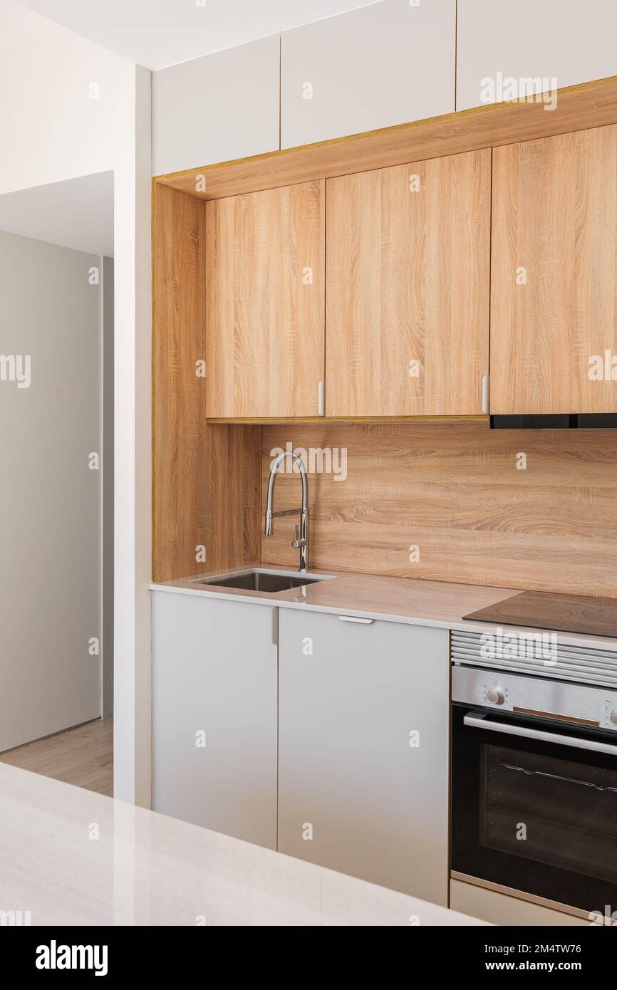 Along the wall is a modern kitchen with light wood cabinets. The marble ...