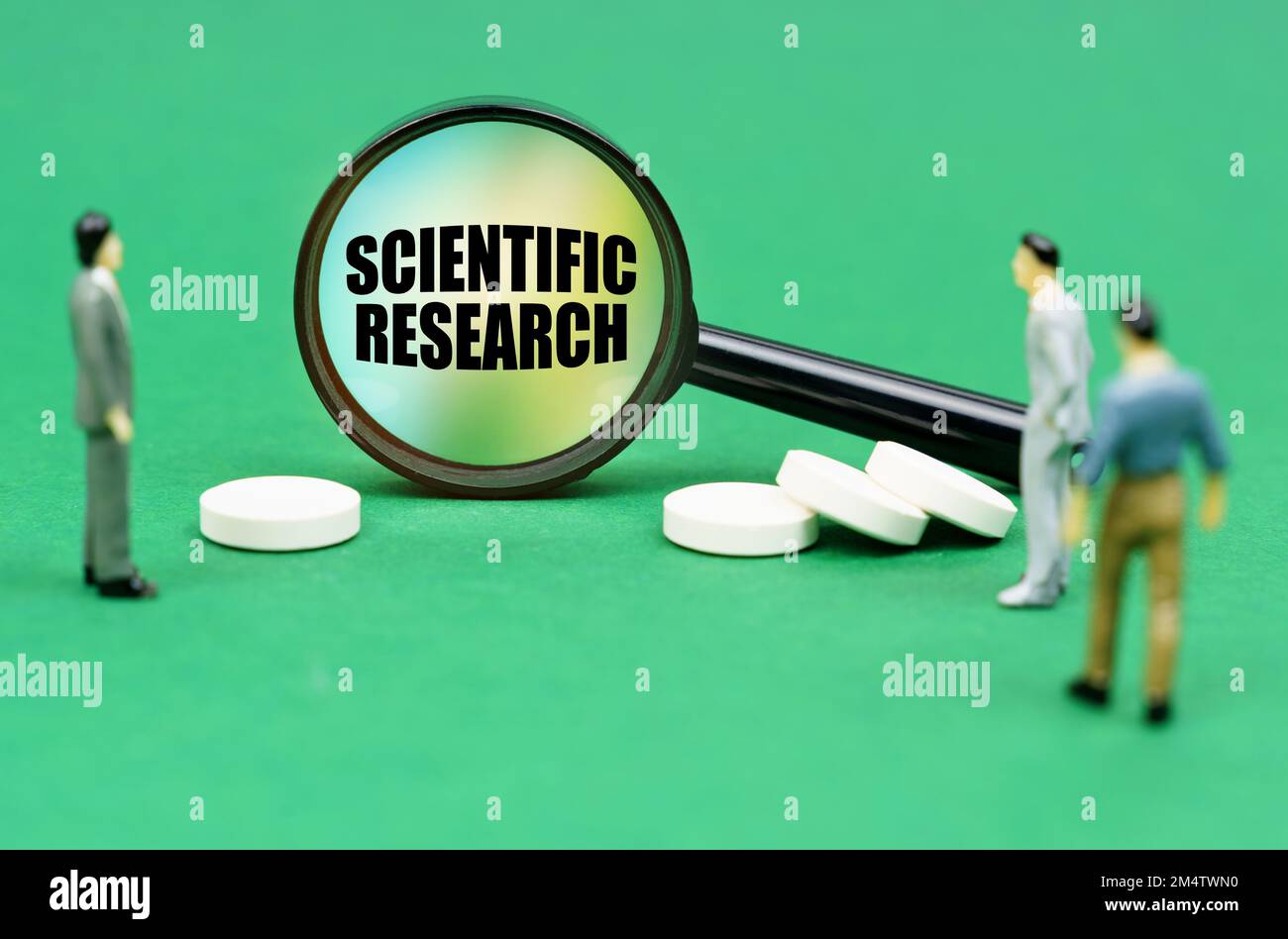 Medical concept. On a green surface are pills, miniature figures of ...