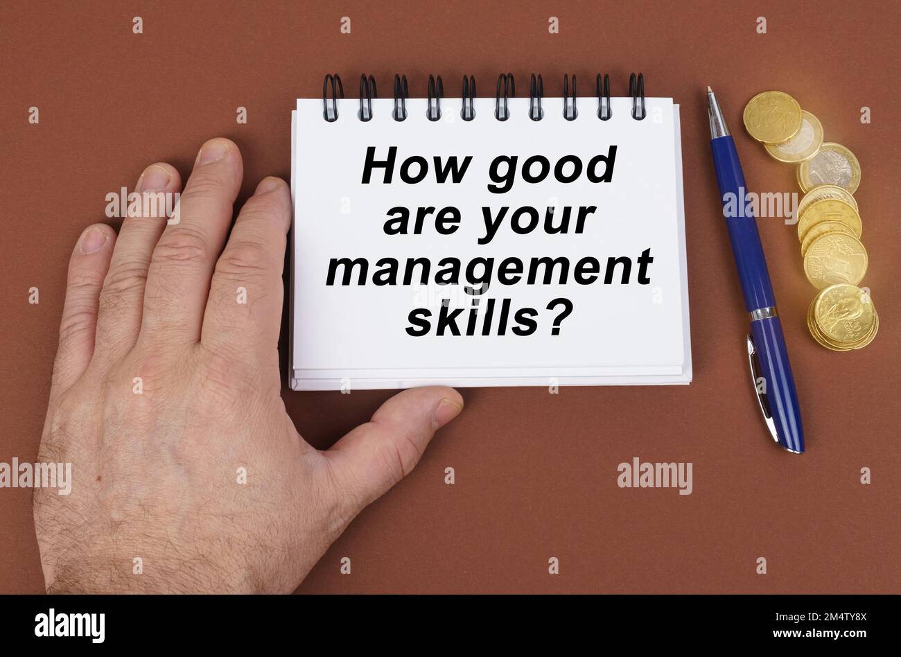 Business concept. On a brown surface are coins, a pen and a notepad ...