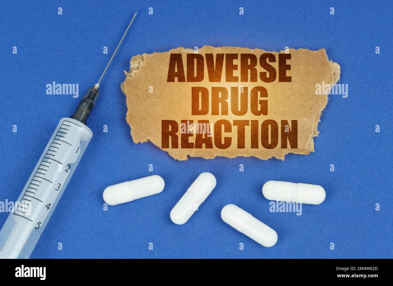 Medical concept. On a blue surface lie a syringe, pills and a cardboard ...
