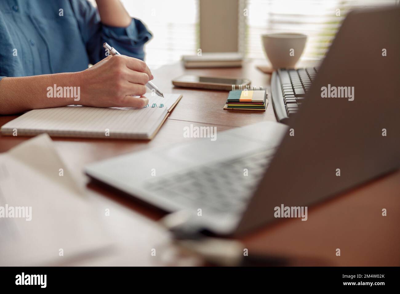 Close up of woman hands taking notes while working in cozy home office ...