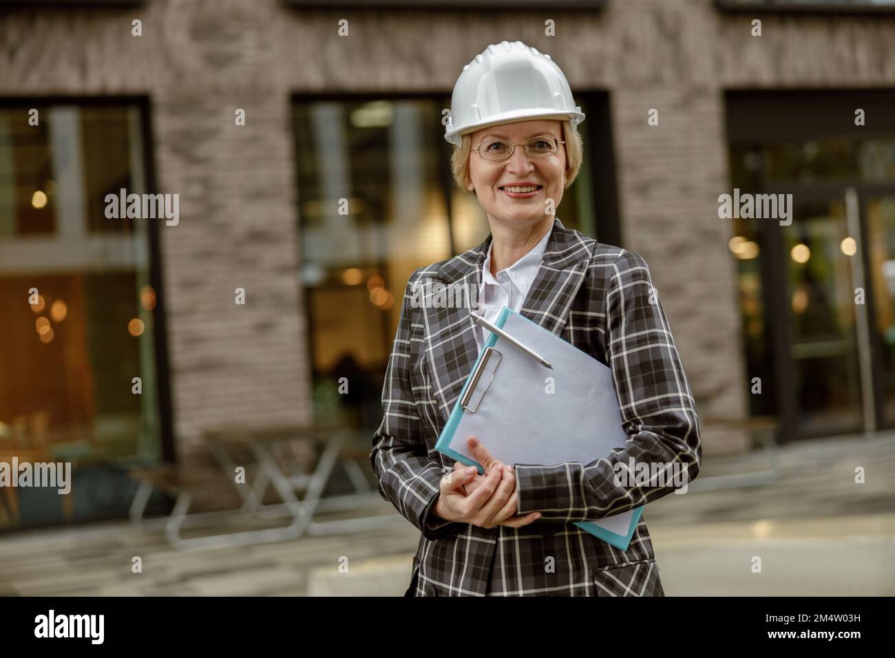 Senior female engineer in suit with white safety helmet holding tablet ...