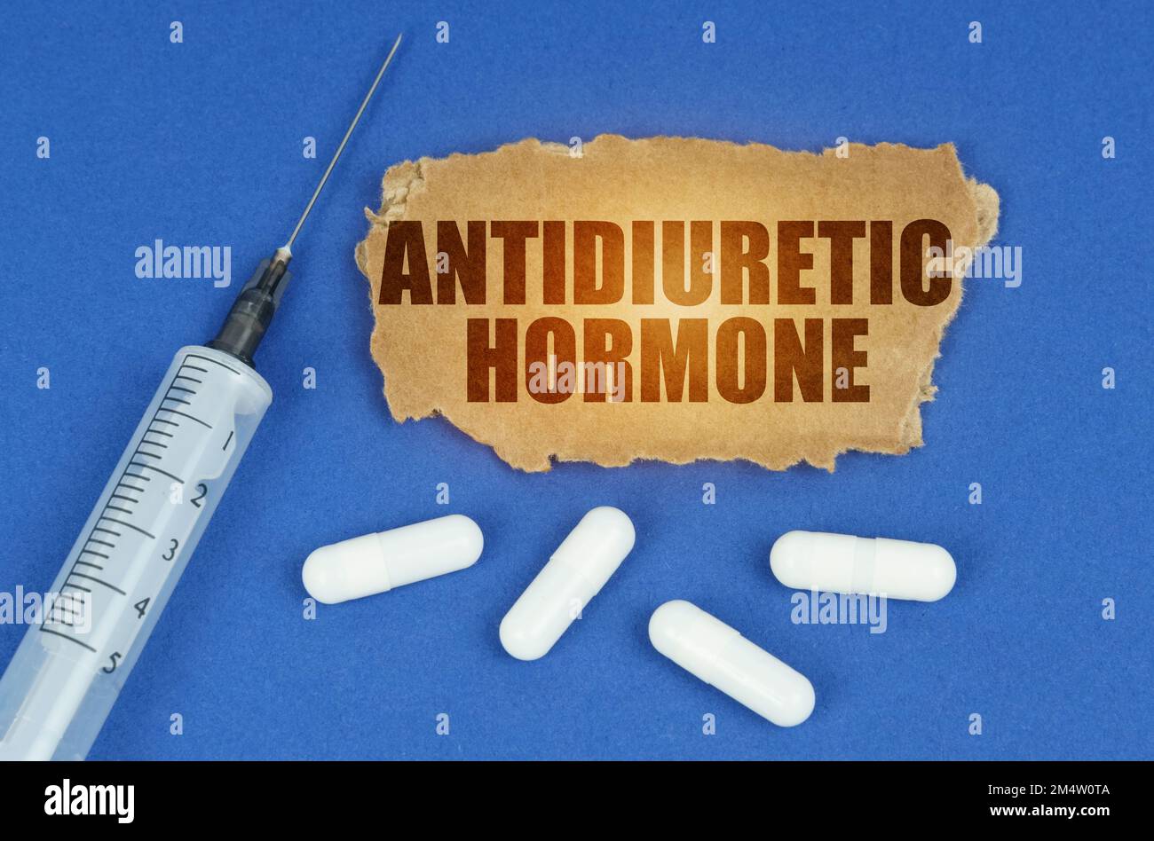 Medical concept. On a blue surface lie a syringe, pills and a cardboard ...