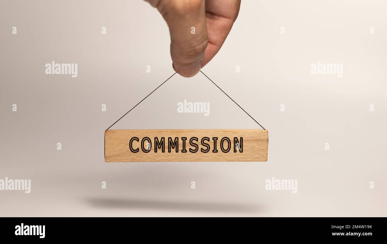 The word commission. Written on wooden sign hanging in human hand Stock ...