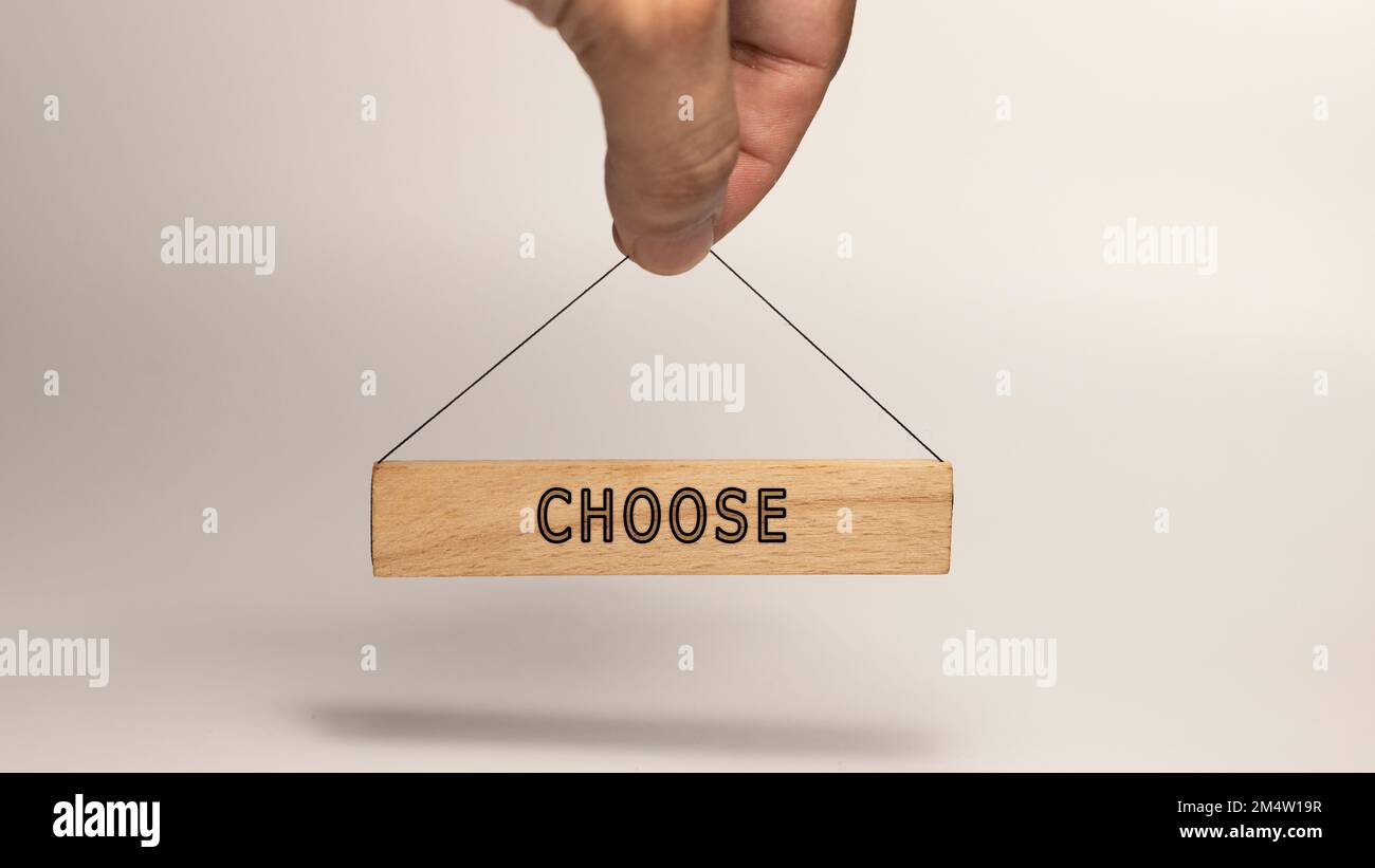 The word choose. Written on wooden sign hanging in human hand Stock ...