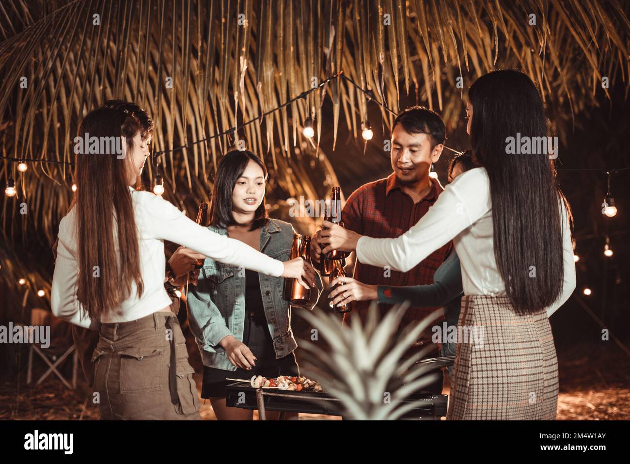 Group of Asian friends having fun barbecuing and drinking beer in the ...