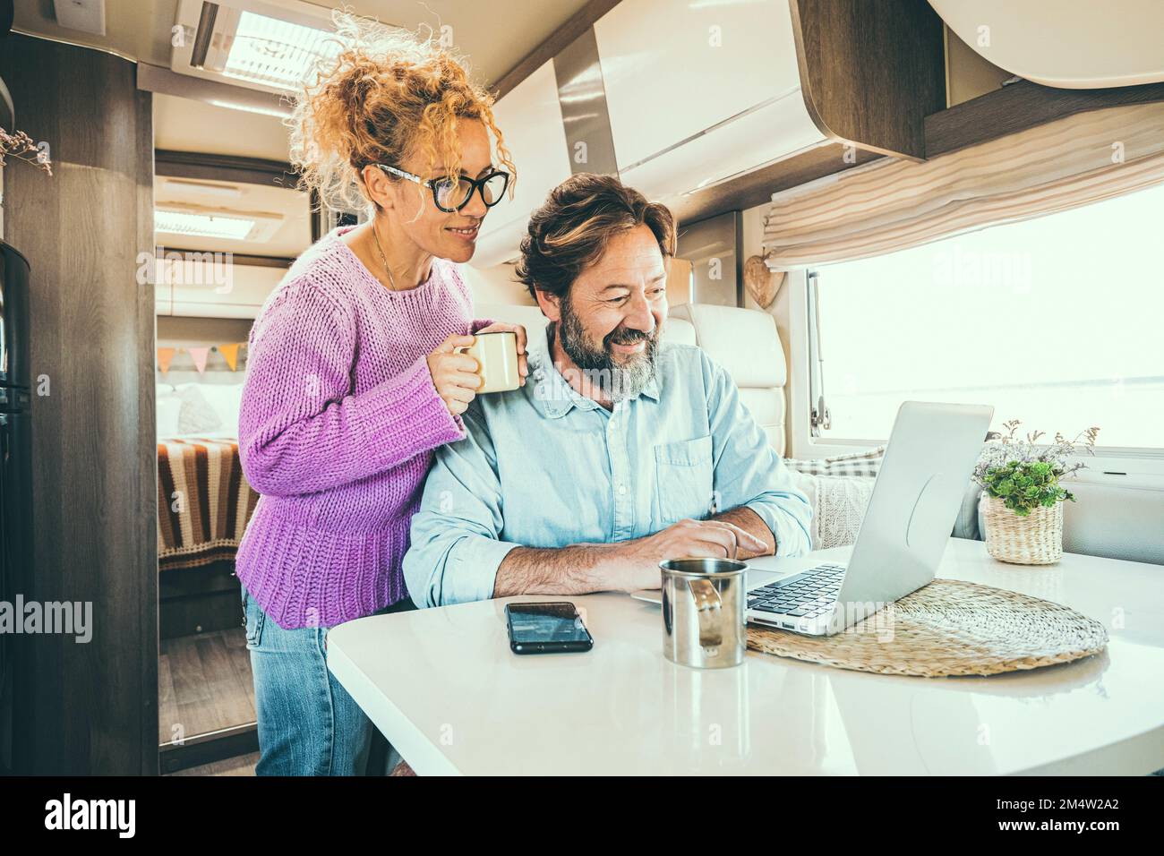 Happy couple man and woman working and using together a laptop computer ...