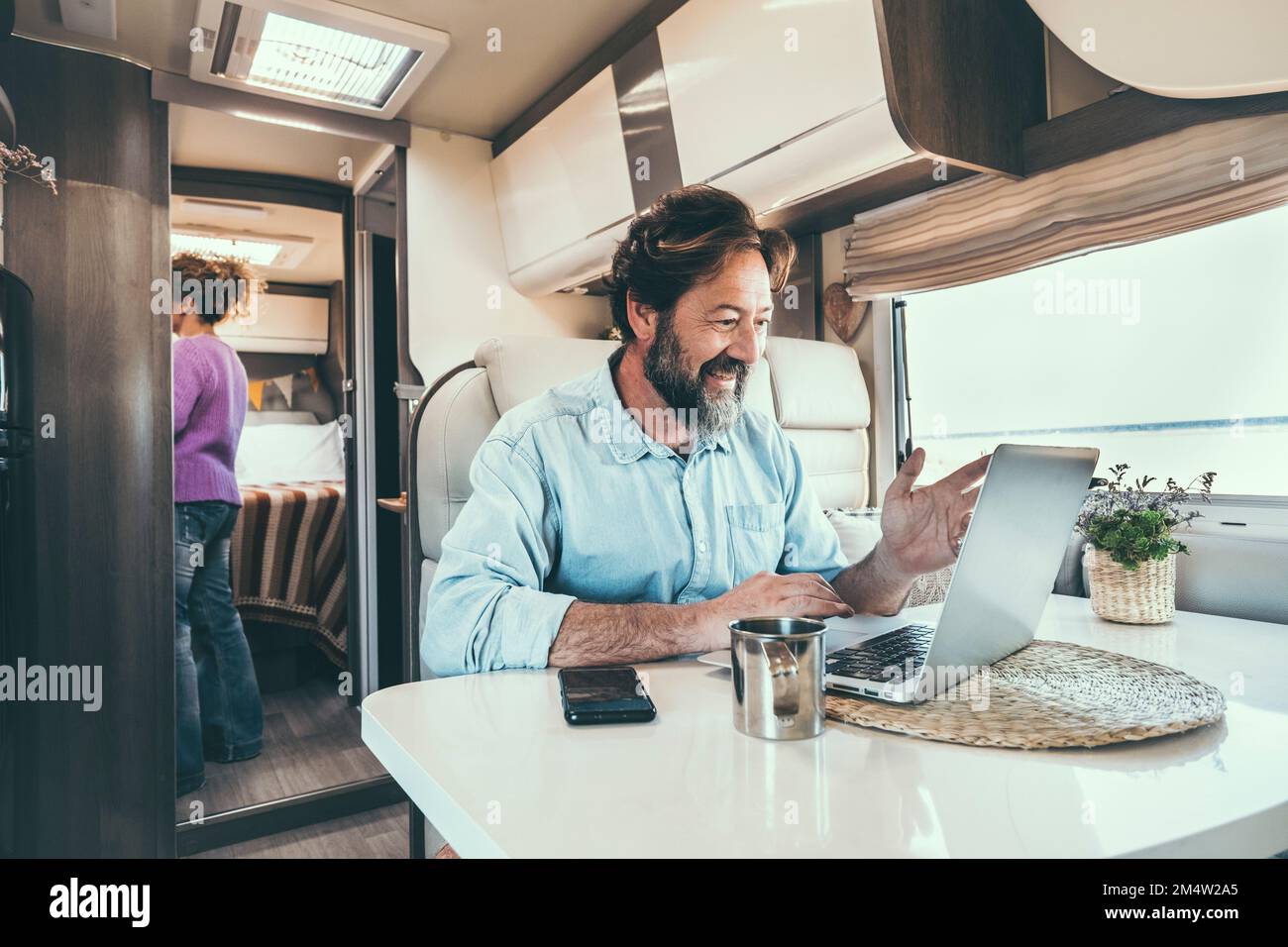 Man and woman living off grid inside a modern camper working on laptop ...