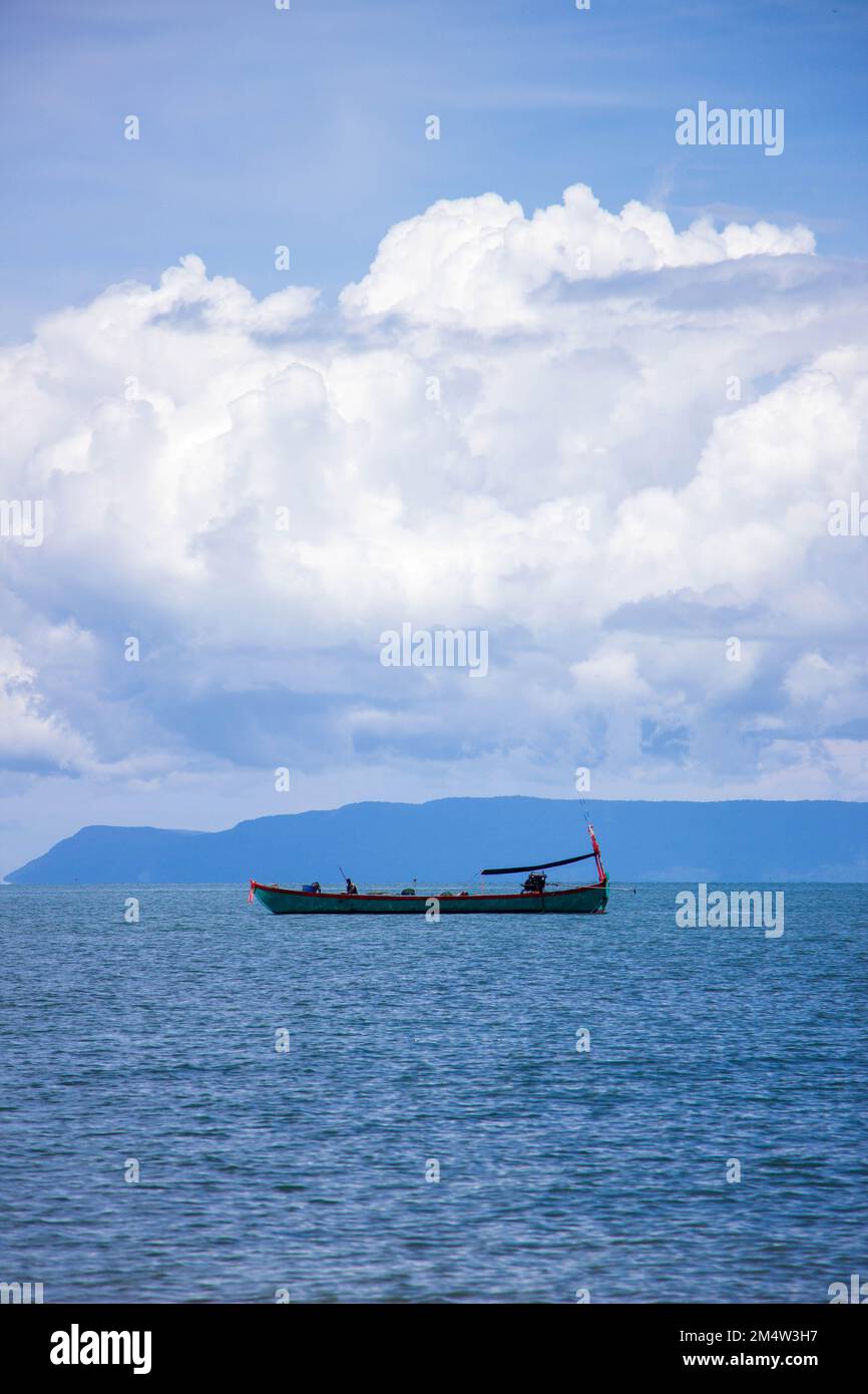 A vertical side view of small boat in the sea under blue cloudy sky ...
