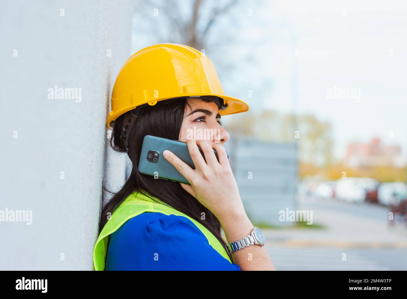 young latin woman engineer with safety helmet and vest, standing ...
