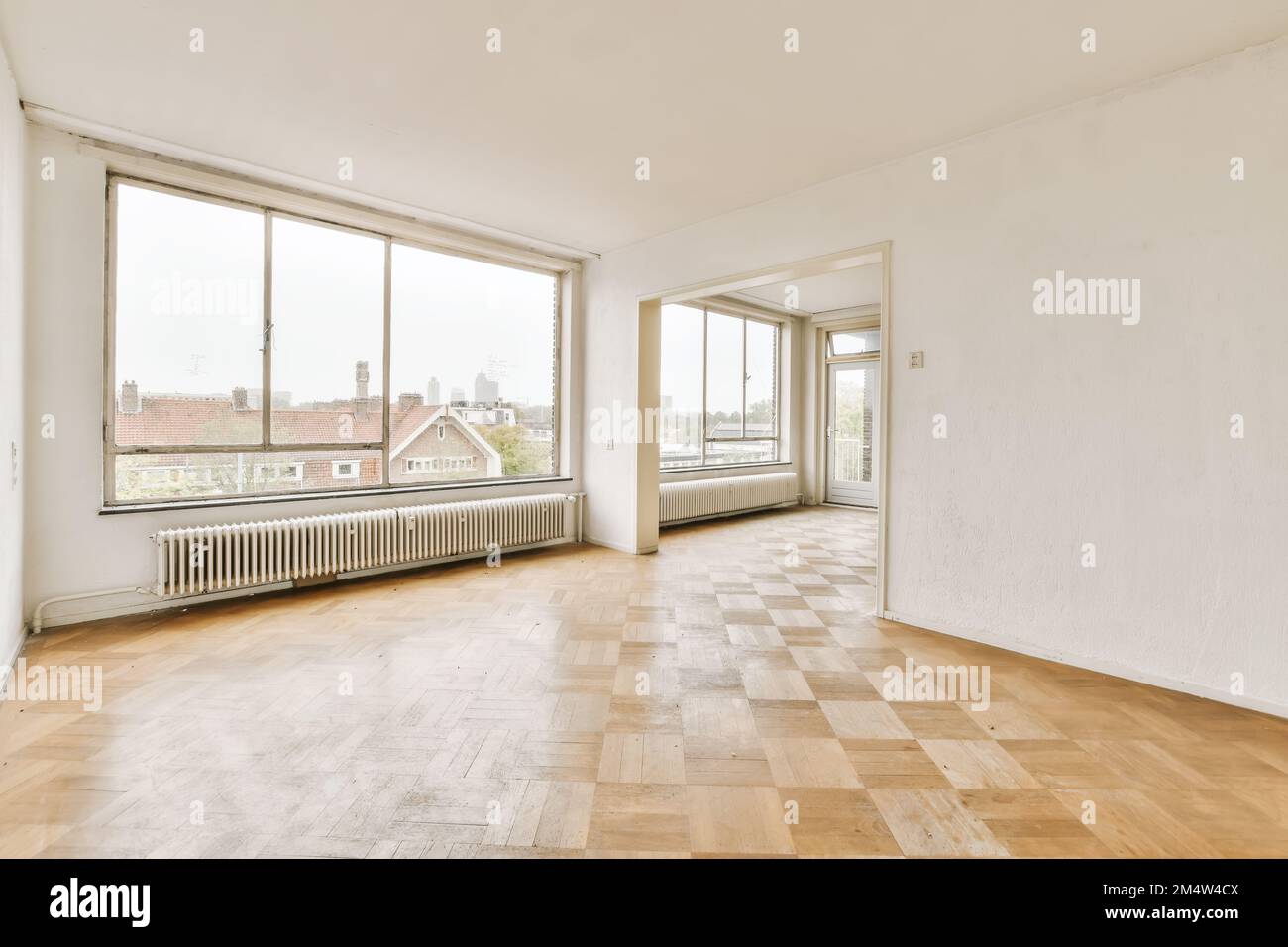 an empty room with wood flooring and large windows looking out onto the ...