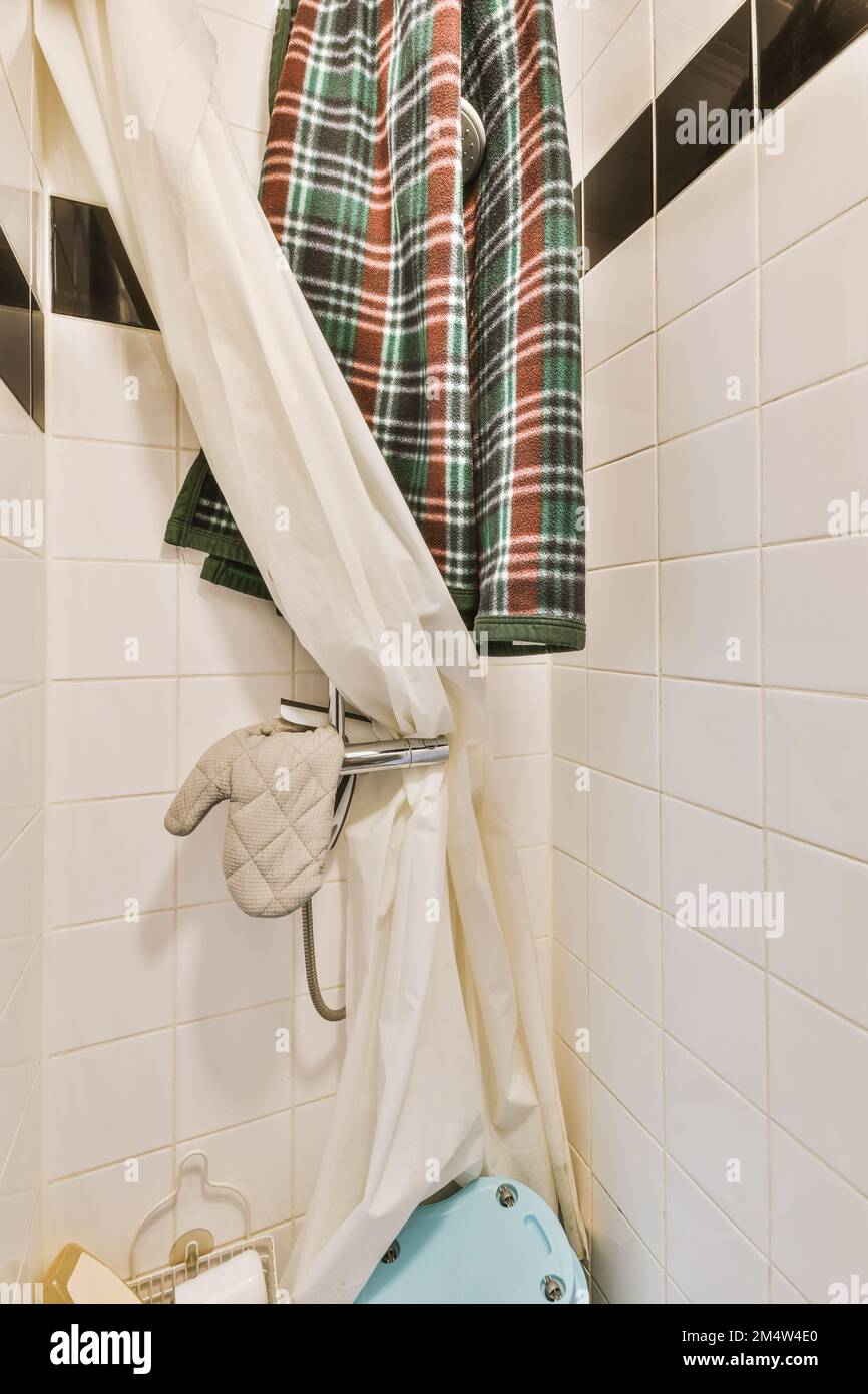 some clothes hanging on a wall in a room with white tiles and black ...