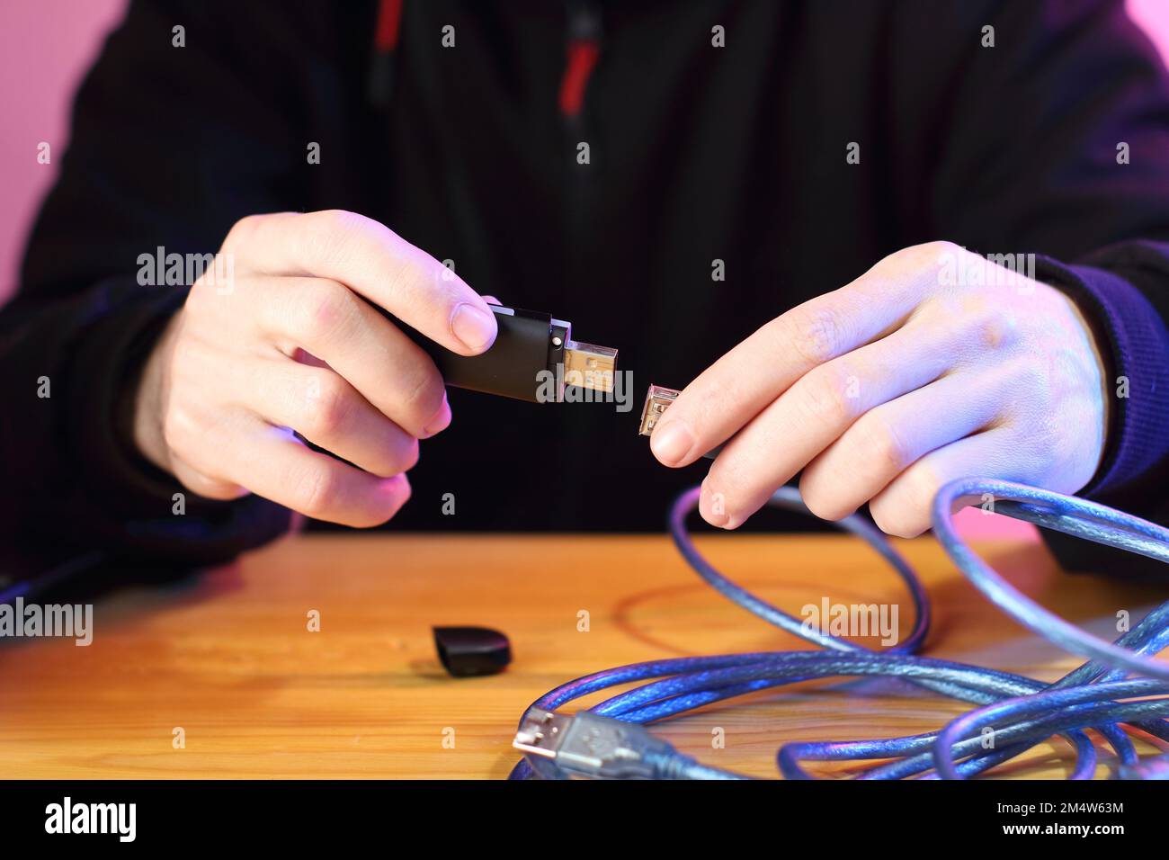 black gsm modem in the fingers of a hand connected to a usb cable ...