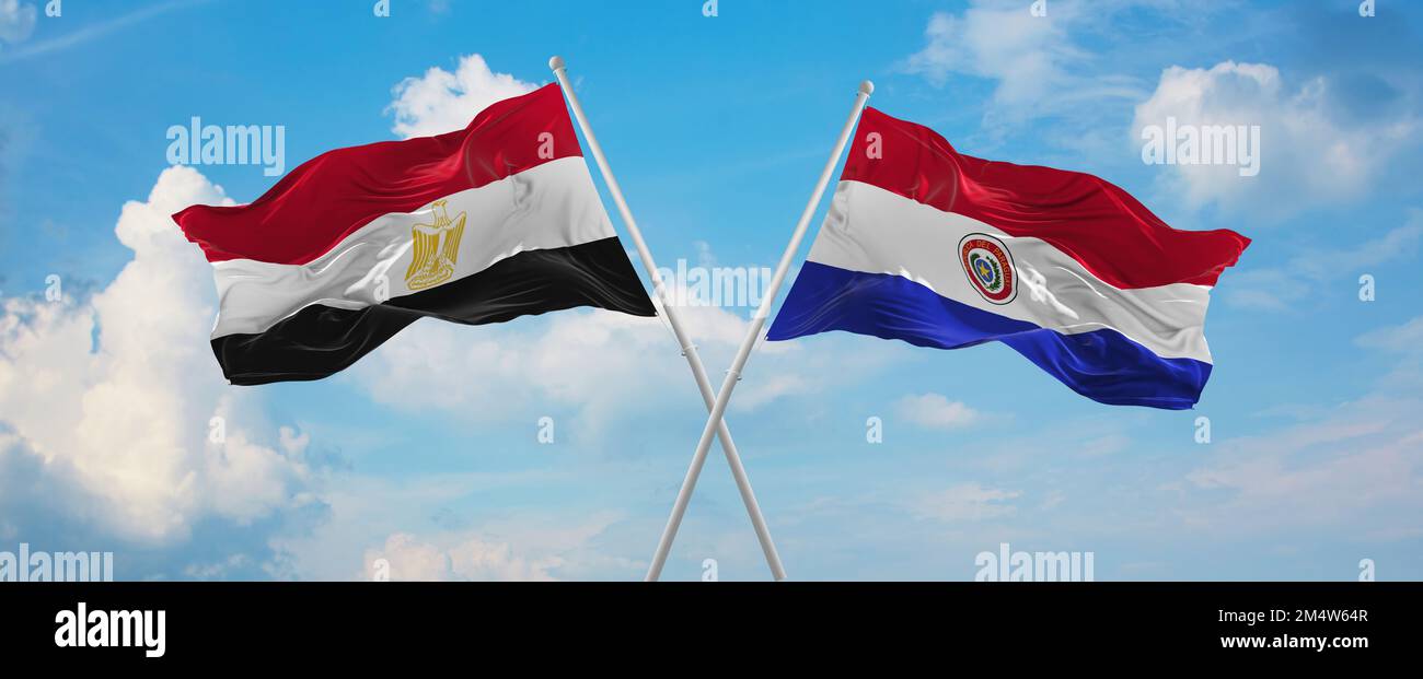 two crossed flags Paraguay and Egypt waving in wind at cloudy sky ...