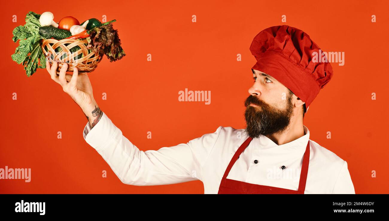 Cook with calm face in burgundy uniform looks at vegetables Stock Photo ...