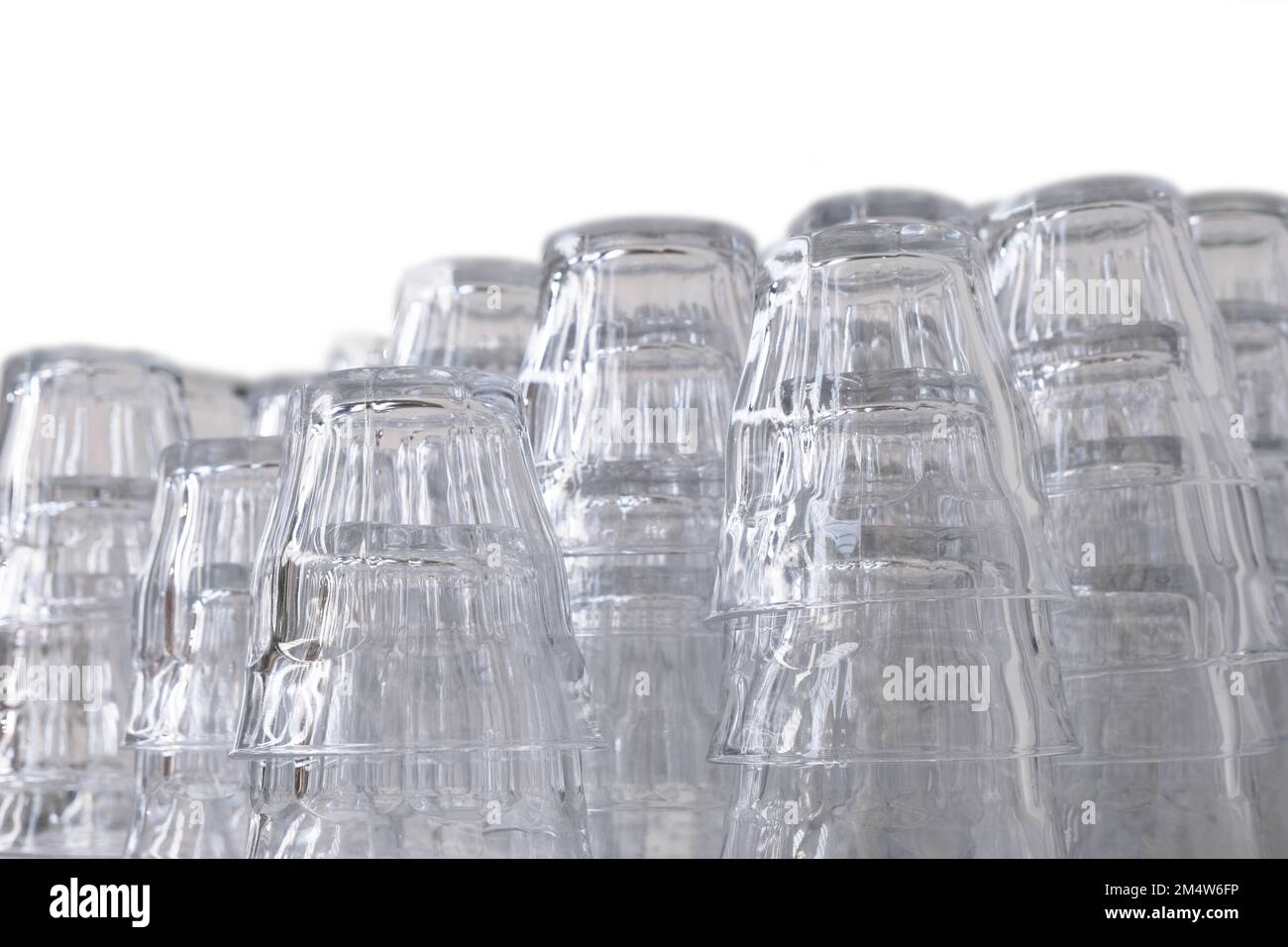 Stacked clear drinking glasses against a white background. Narrow depth ...