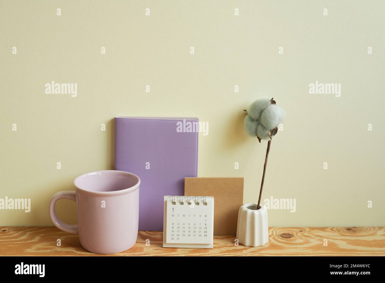 Purple diary notebook, mug cup, calendar, vase of cotton plant on ...