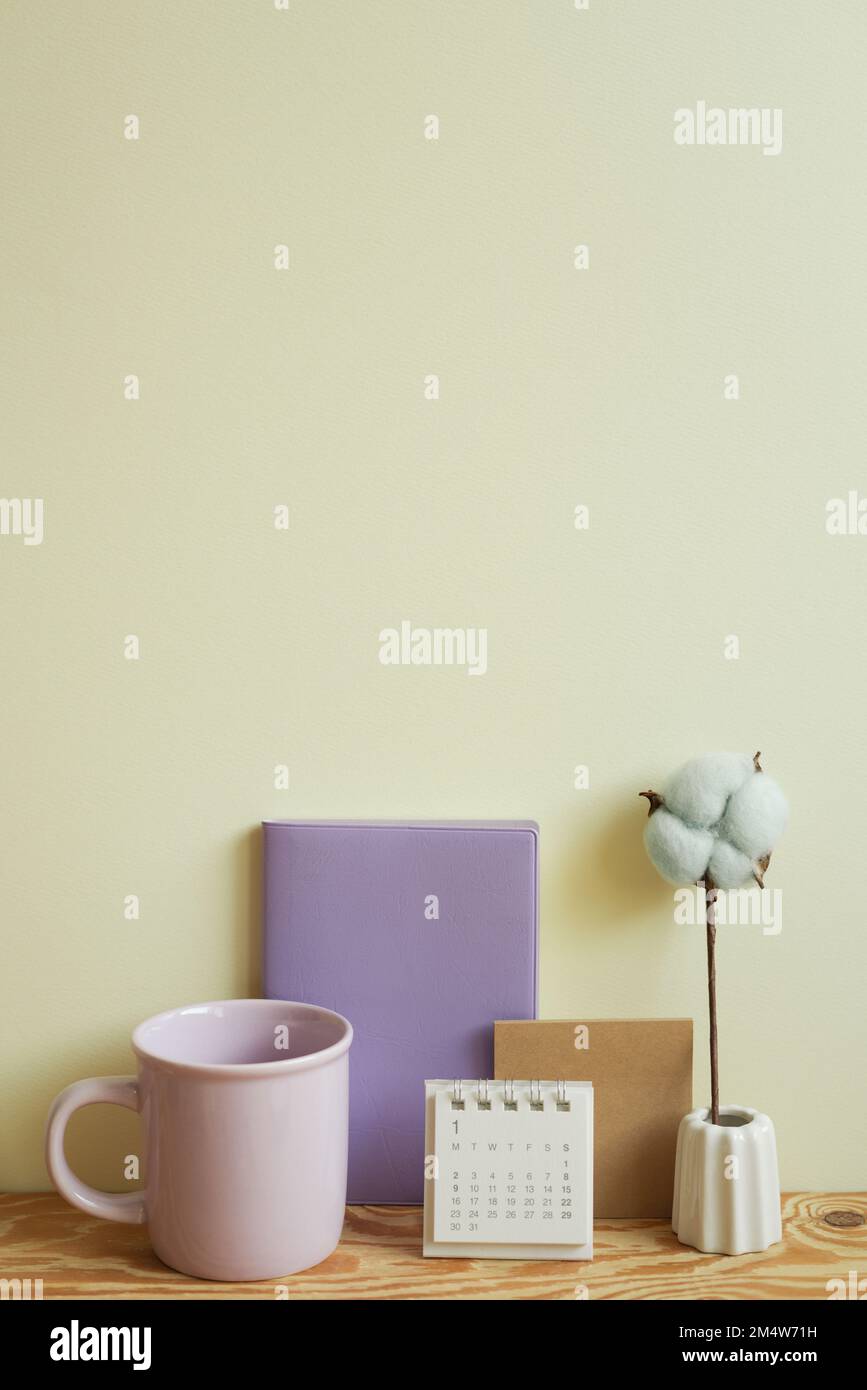 Purple diary notebook, mug cup, calendar, vase of cotton plant on ...