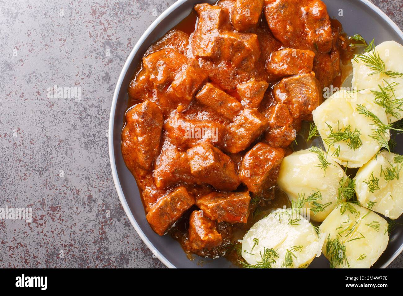 Austrian beef goulash in a thick rich sauce with boiled potatoes close ...