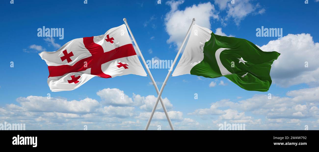 two crossed flags Pakistan and Georgia waving in wind at cloudy sky ...