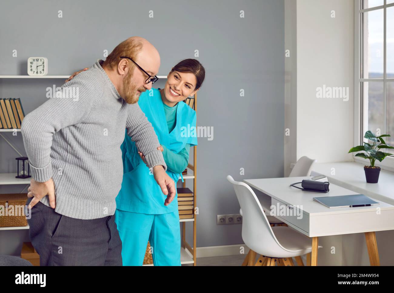 Smiling nurse helping retired senior man while walking, holding his hand, supporting him Stock ...