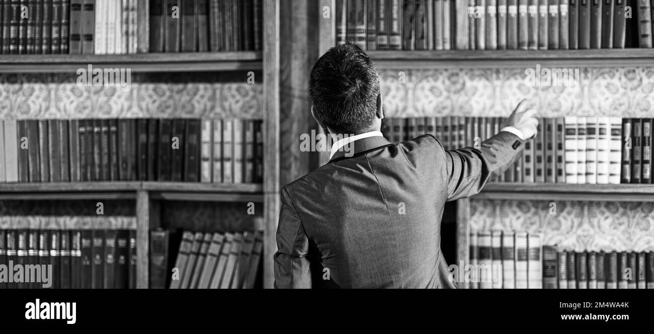 Man takes book from bookcase. Student stands in library and choose book ...