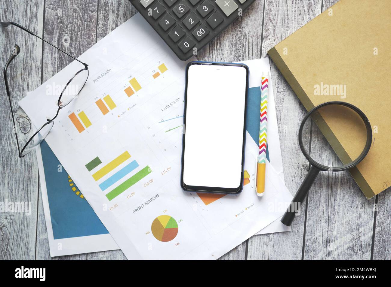 top view of smart phone with empty screen and financial chart on table ...