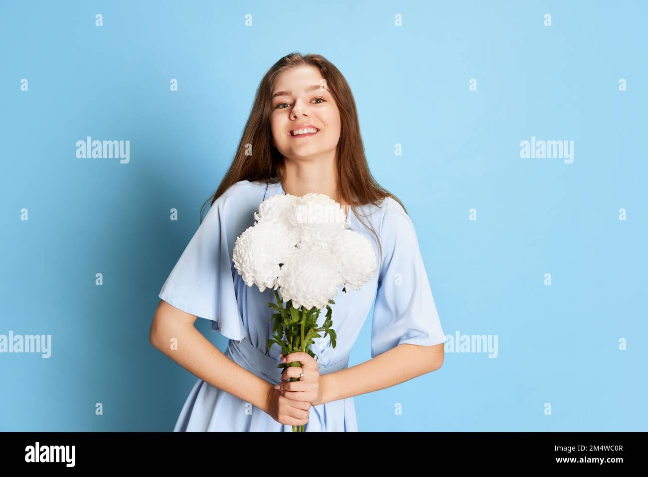 Portrait of happy young girl in cute tender dress posing with white ...