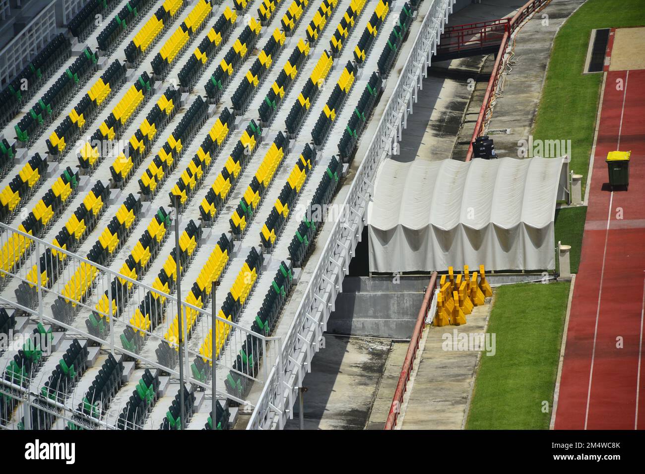 front row yellow seat on a green football stadium with a red track ...