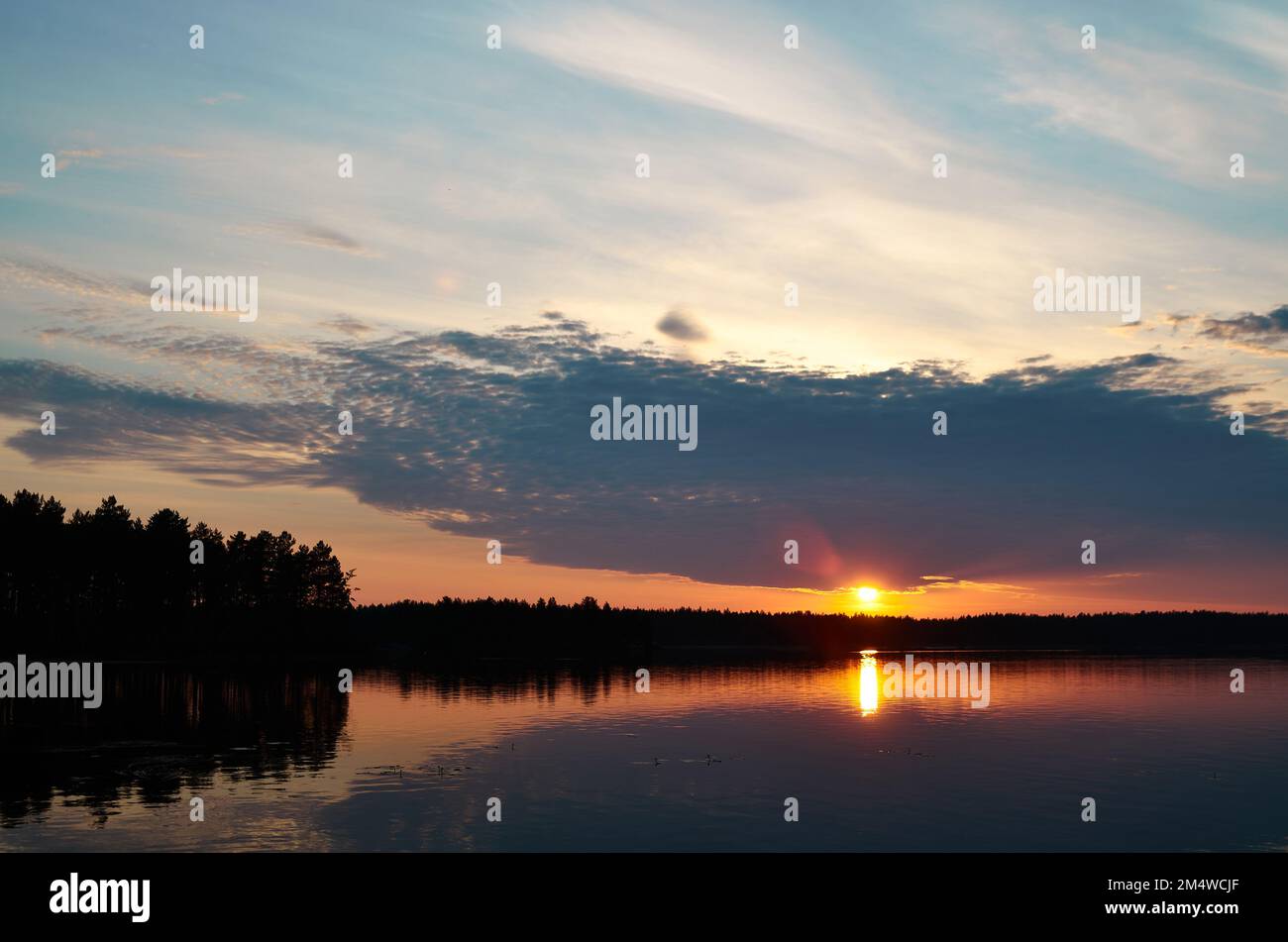 Sunset in a cloudy sky over the water surface Stock Photo - Alamy