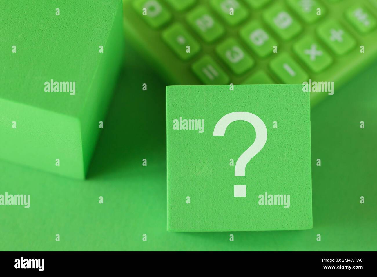 Question mark sign on block cube, green calculator, green background ...