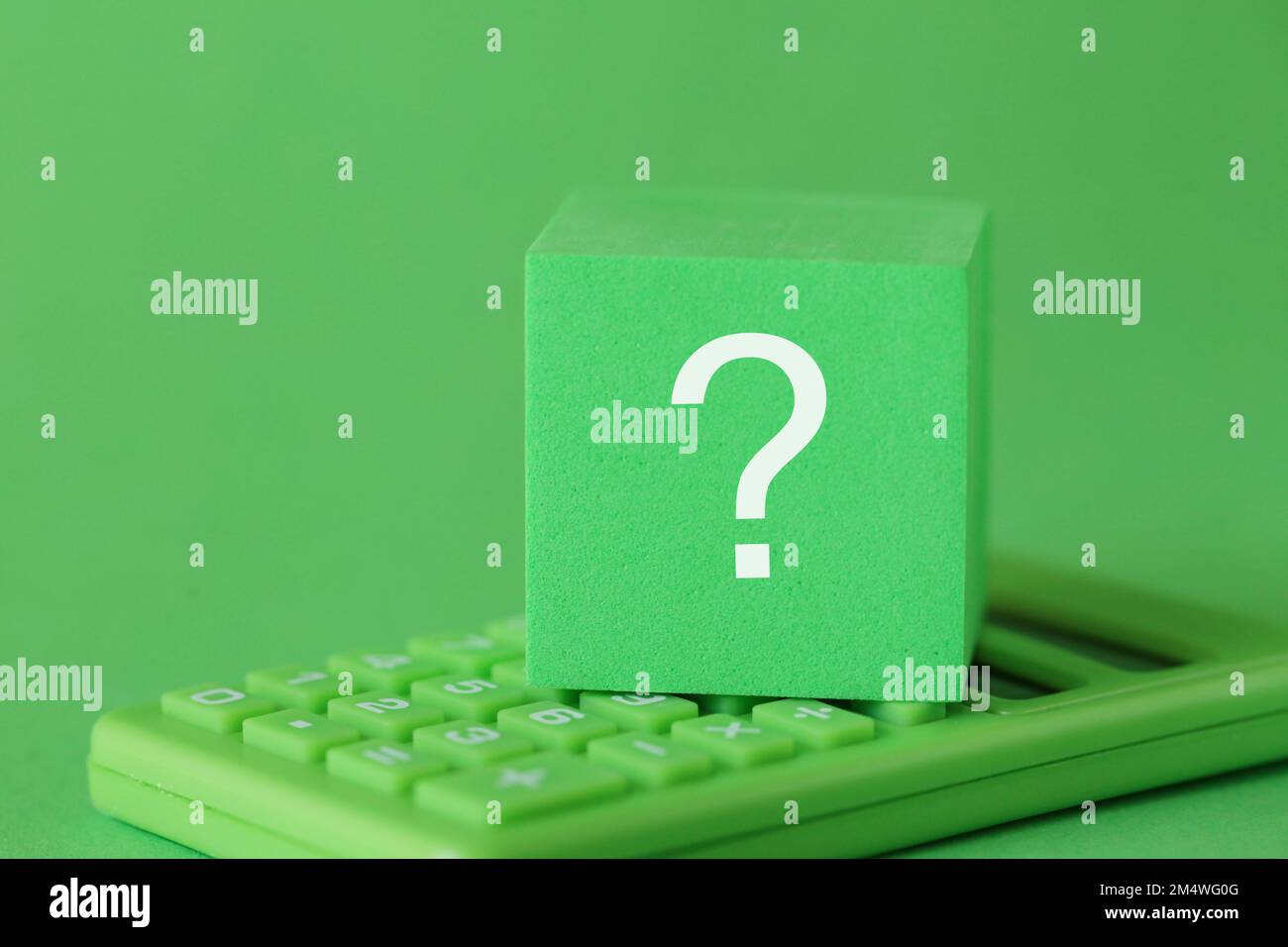 Question mark sign on block cube, green calculator on green background ...
