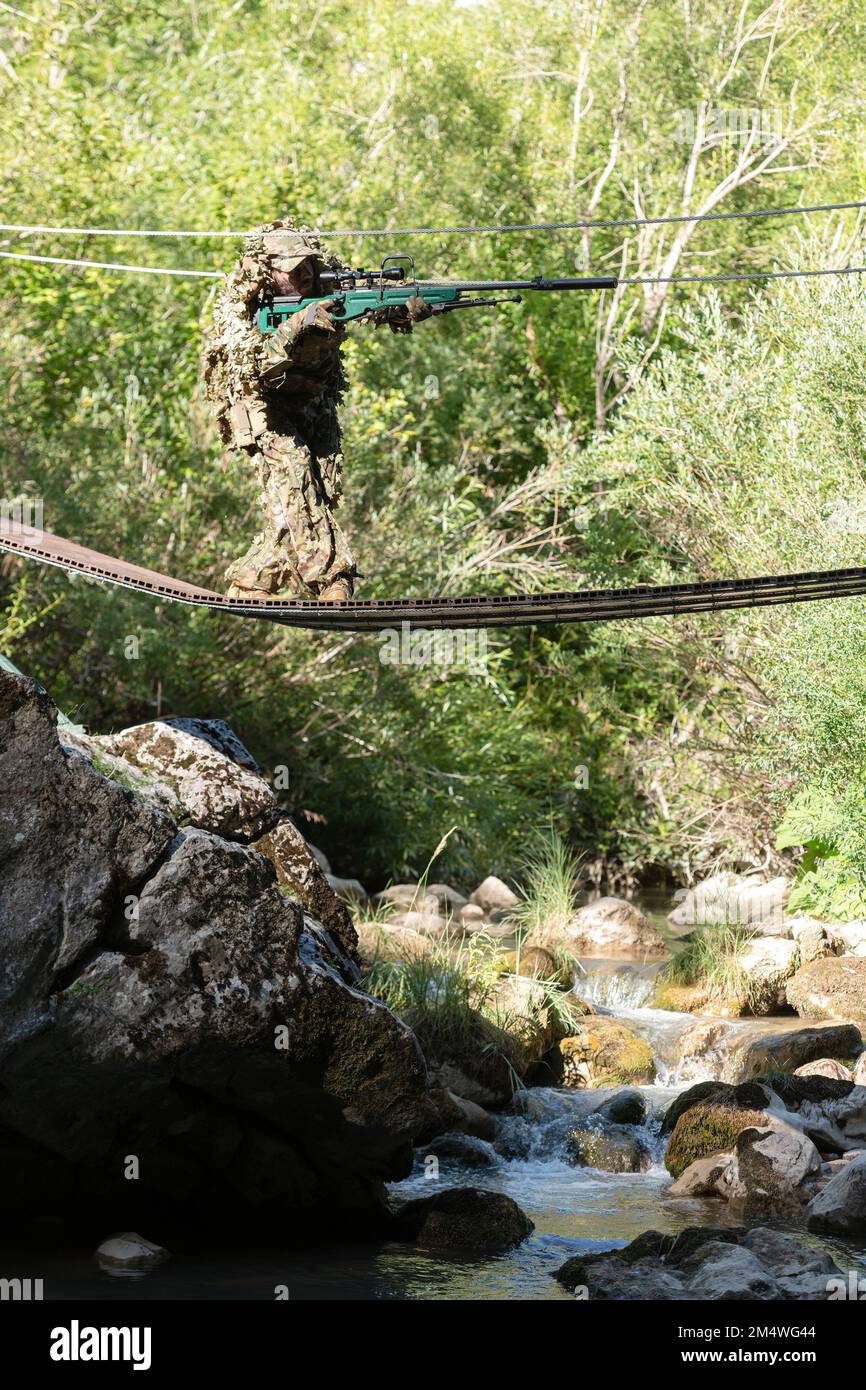 A military man or airsoft player in a camouflage suit sneaking the rope ...