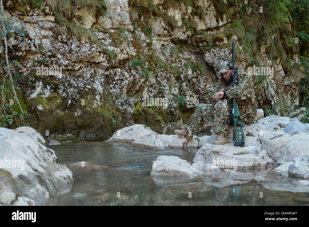 A military man or airsoft player in a camouflage suit sneaking the ...