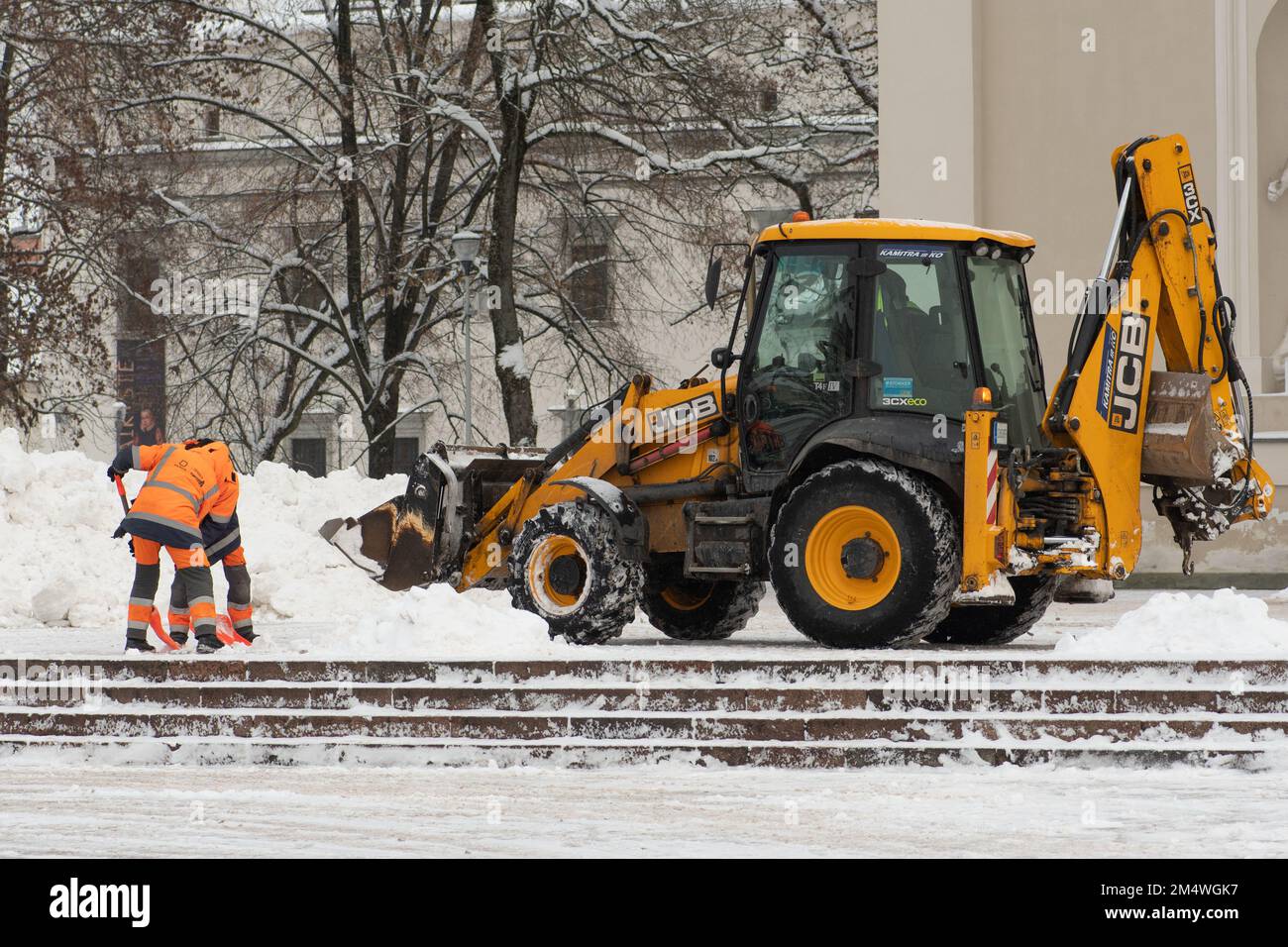 Snowplow and workmen with shovels at work in winter clearing snow in ...