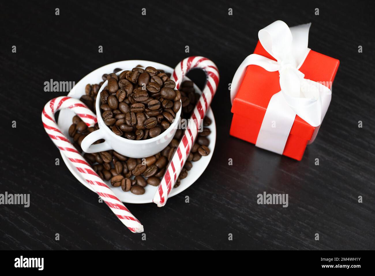 Candy canes coffee beans in white cup and red gift box on dark wooden ...