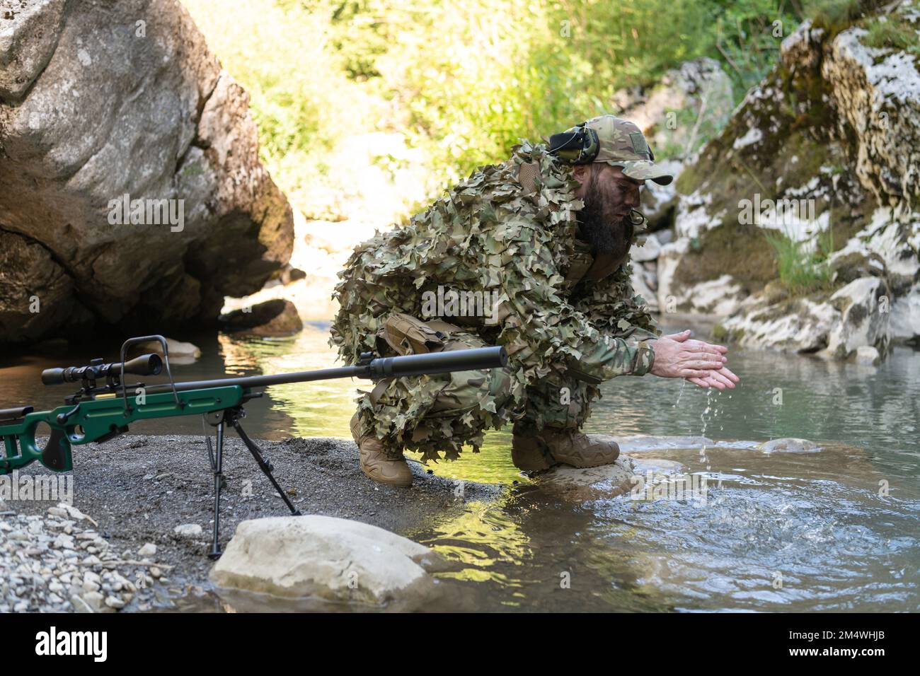 Soldier in a camouflage suit uniform drinking fresh water from the ...