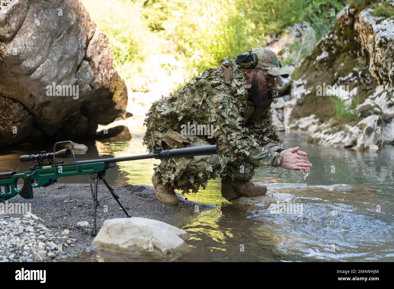 Soldier in a camouflage suit uniform drinking fresh water from the ...