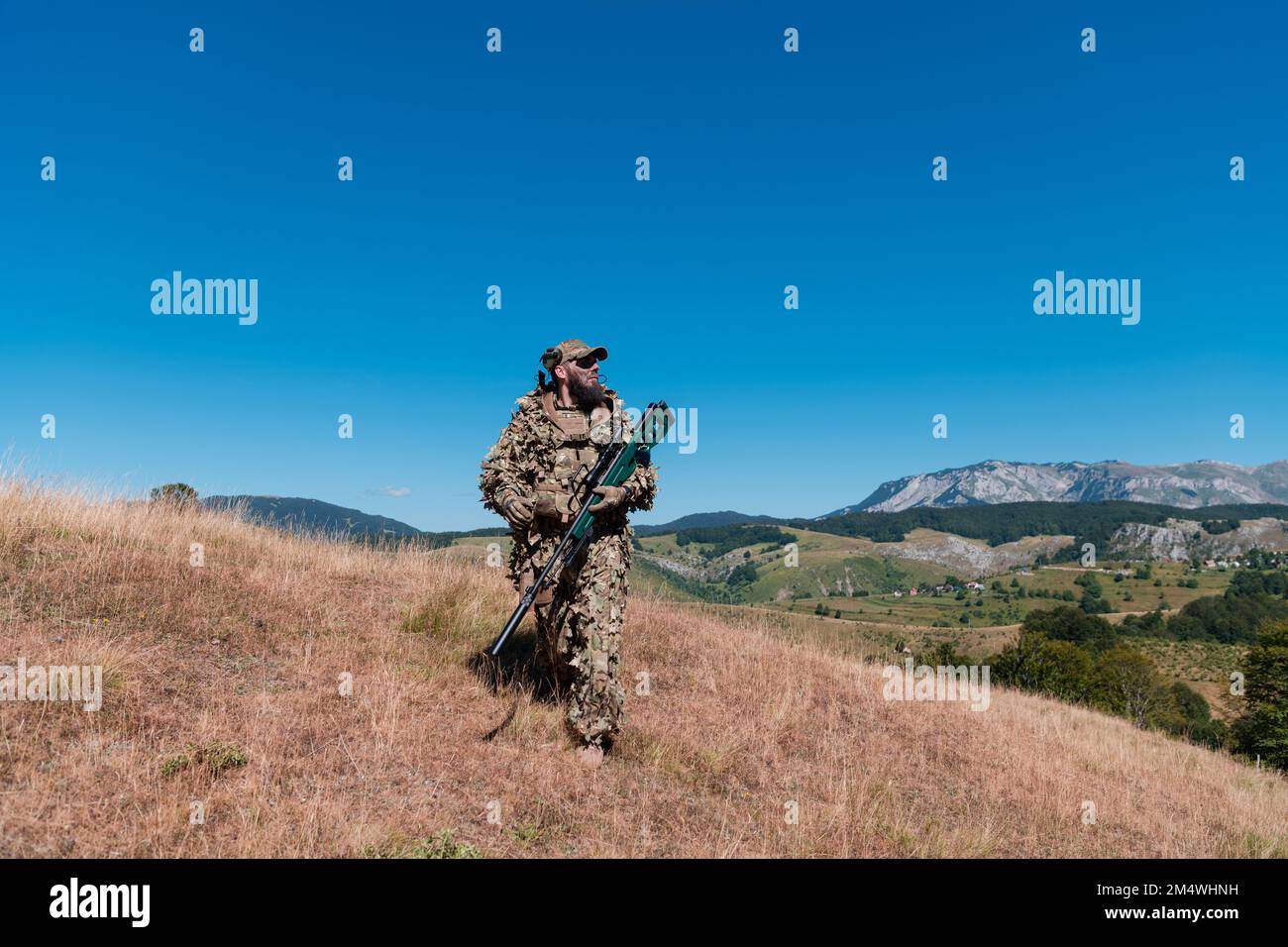 Army soldier holding a sniper rifle with scope and walking in the ...
