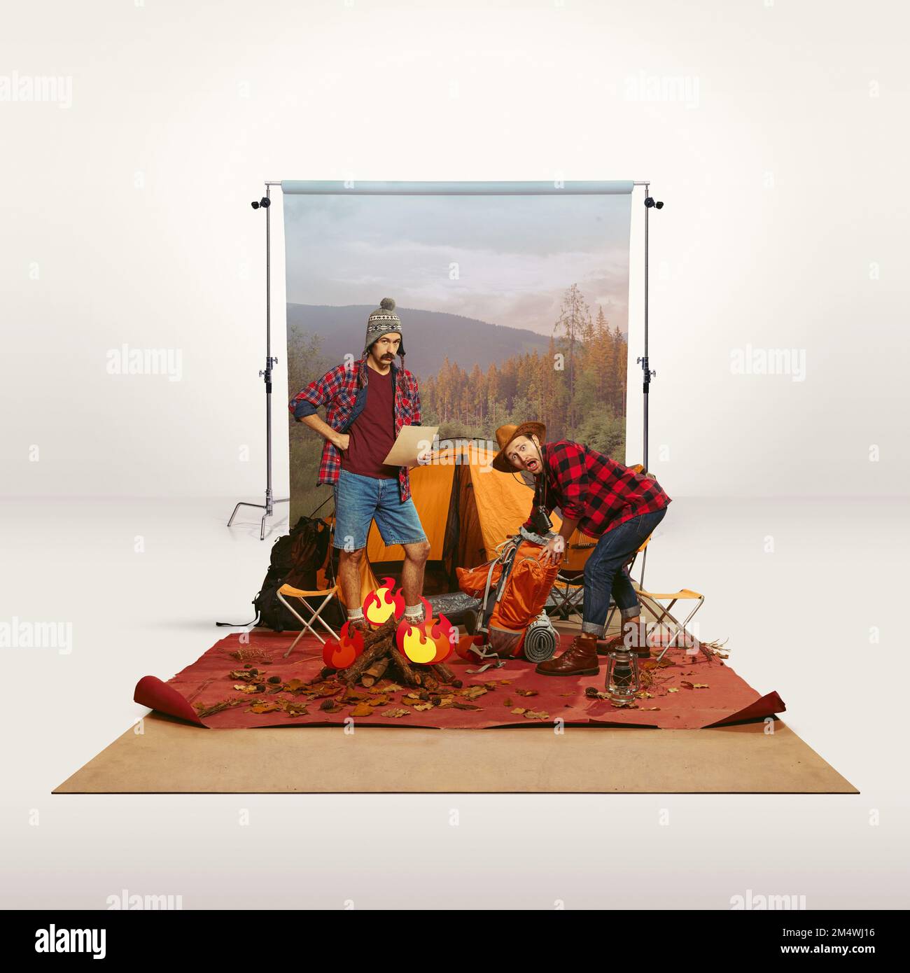 Two mates, men recreating camping activity over grey background with ...