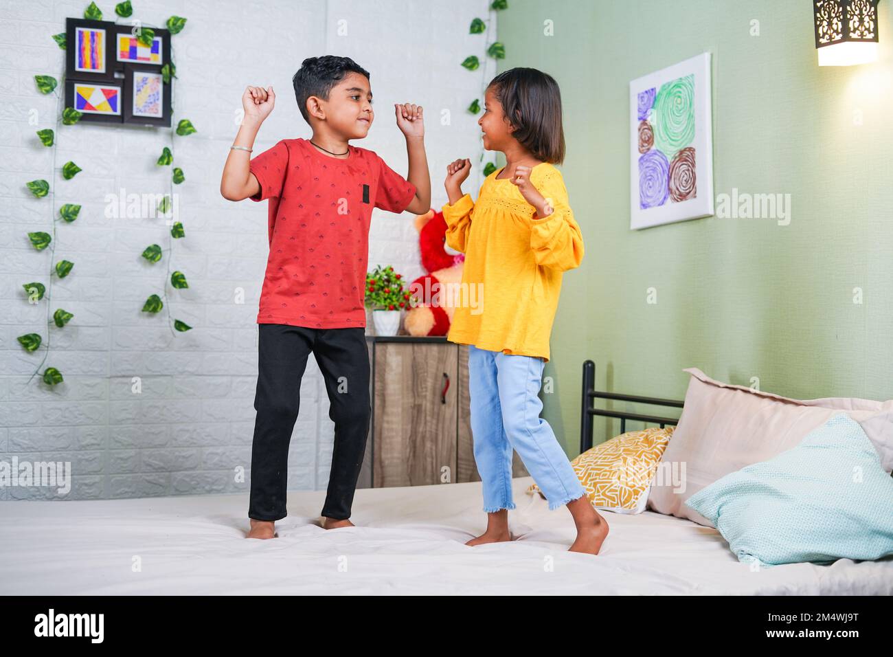 Happy smiling sibling kids dancing by jumping on bed at home - concept ...