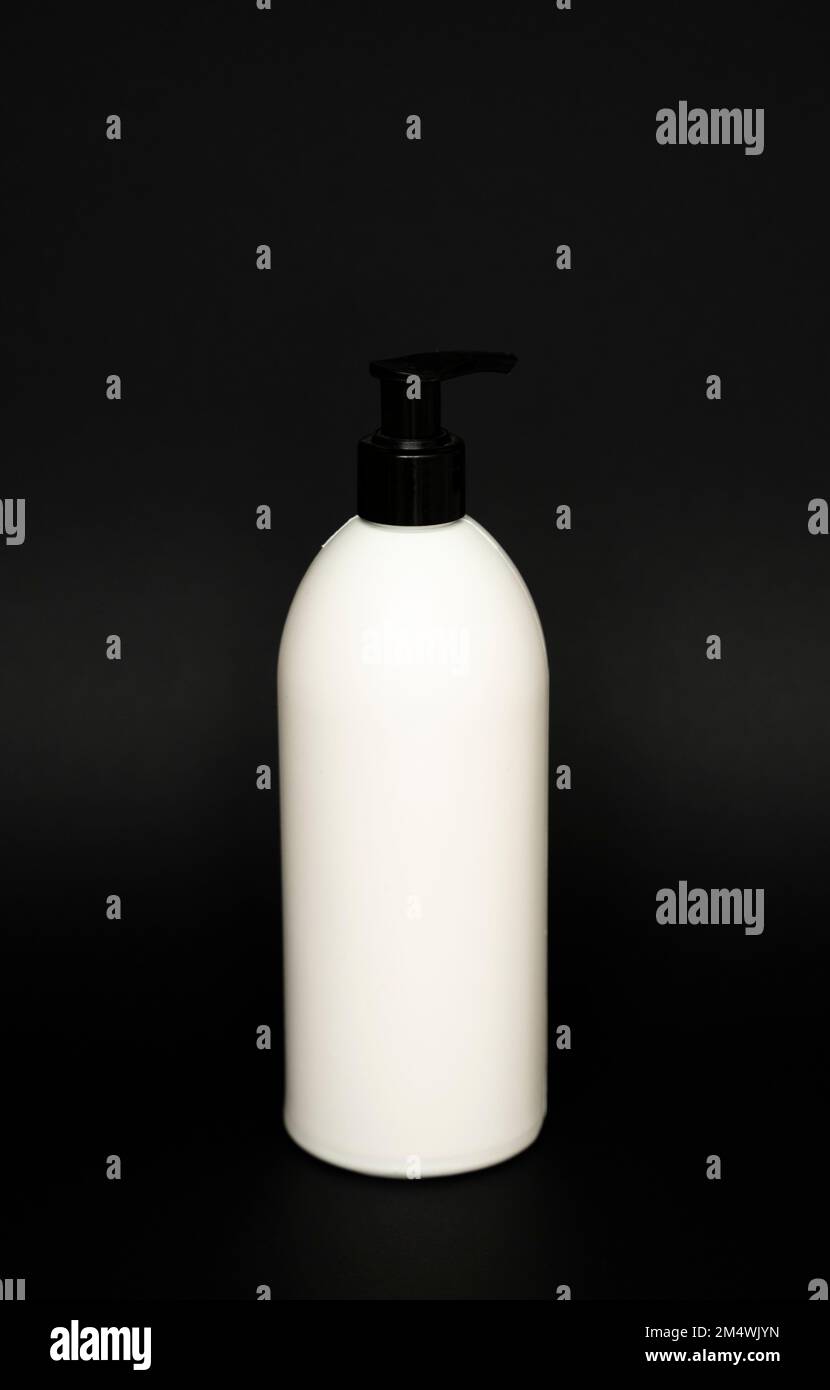 White unbranded bottle with a black dispenser isolated on black ...