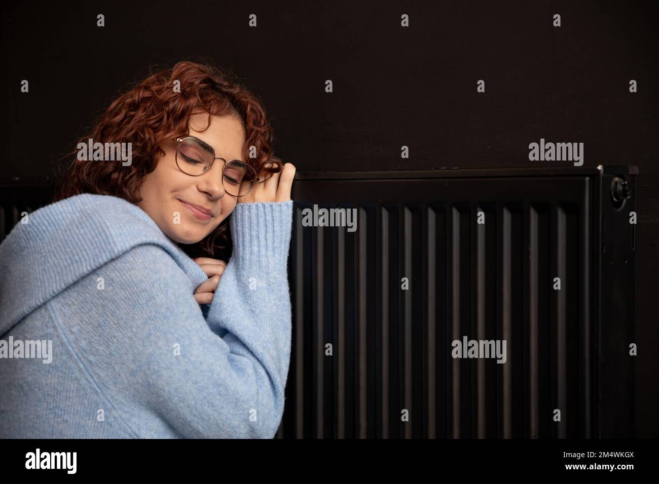 The girl closed her eyes and hugged the warm radiator Stock Photo - Alamy