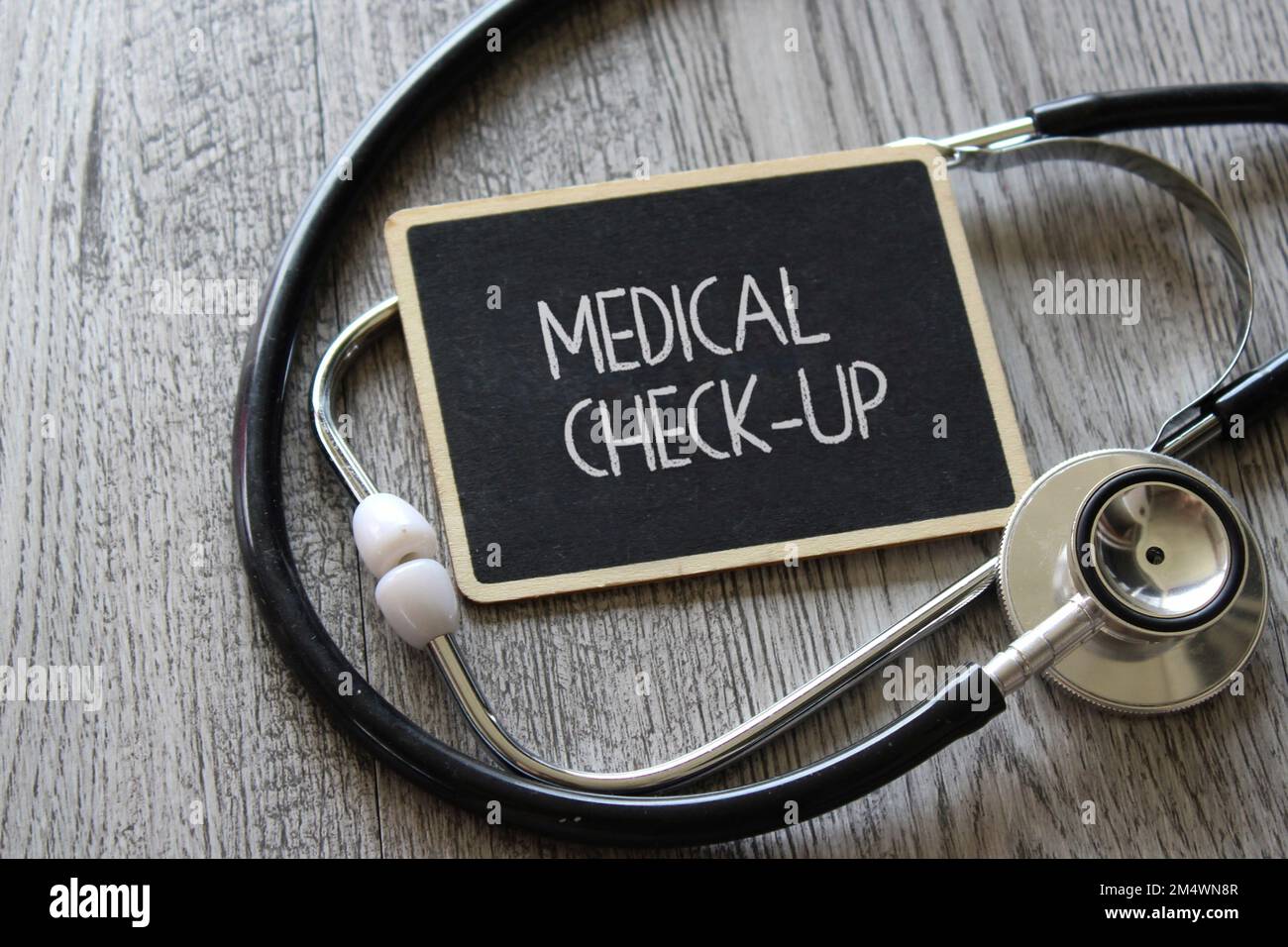 Stethoscope and chalkboard with text MEDICAL CHECK-UP on wooden table ...
