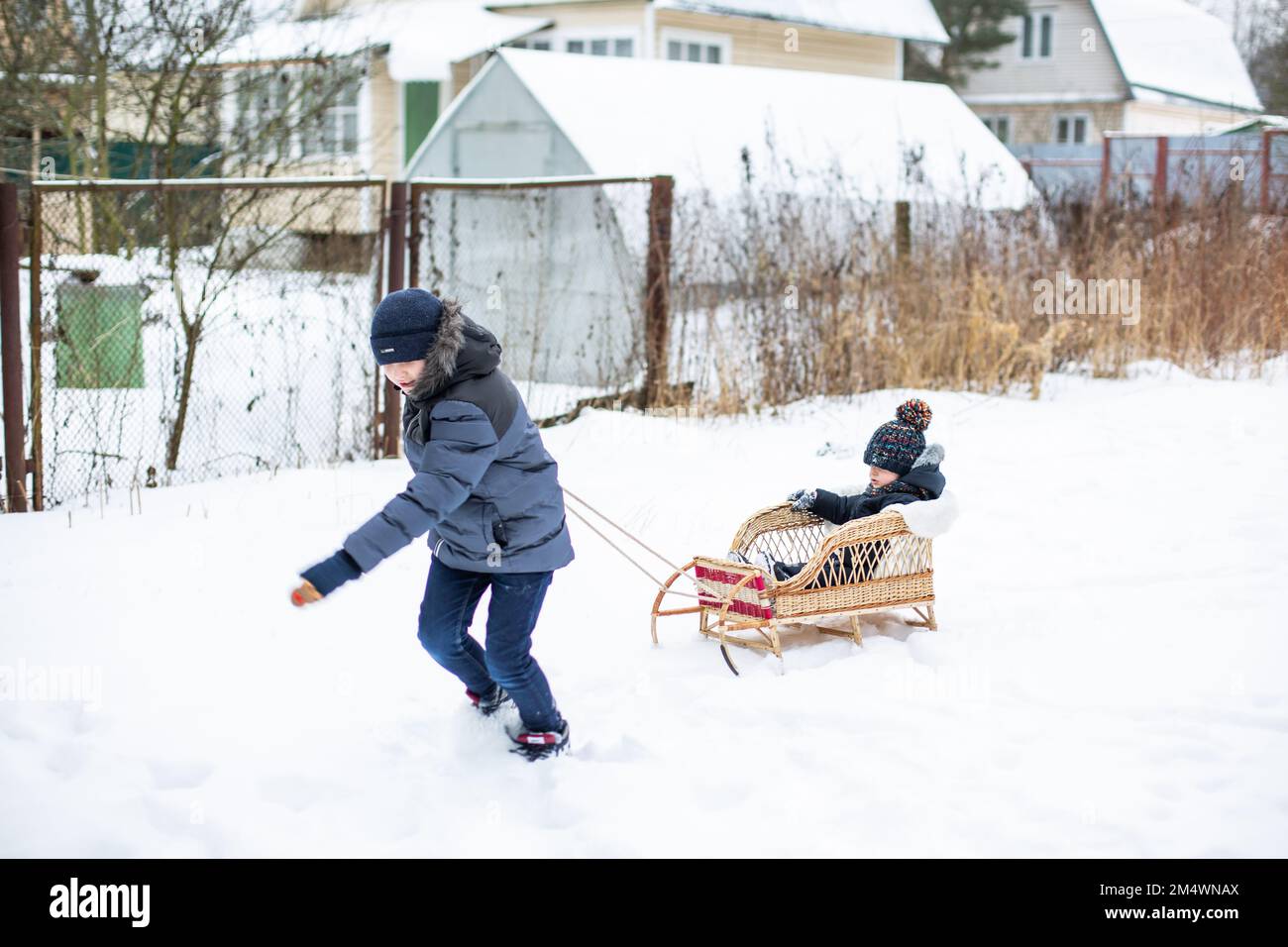 Boy pulling his friend on a sledge Stock Photo - Alamy