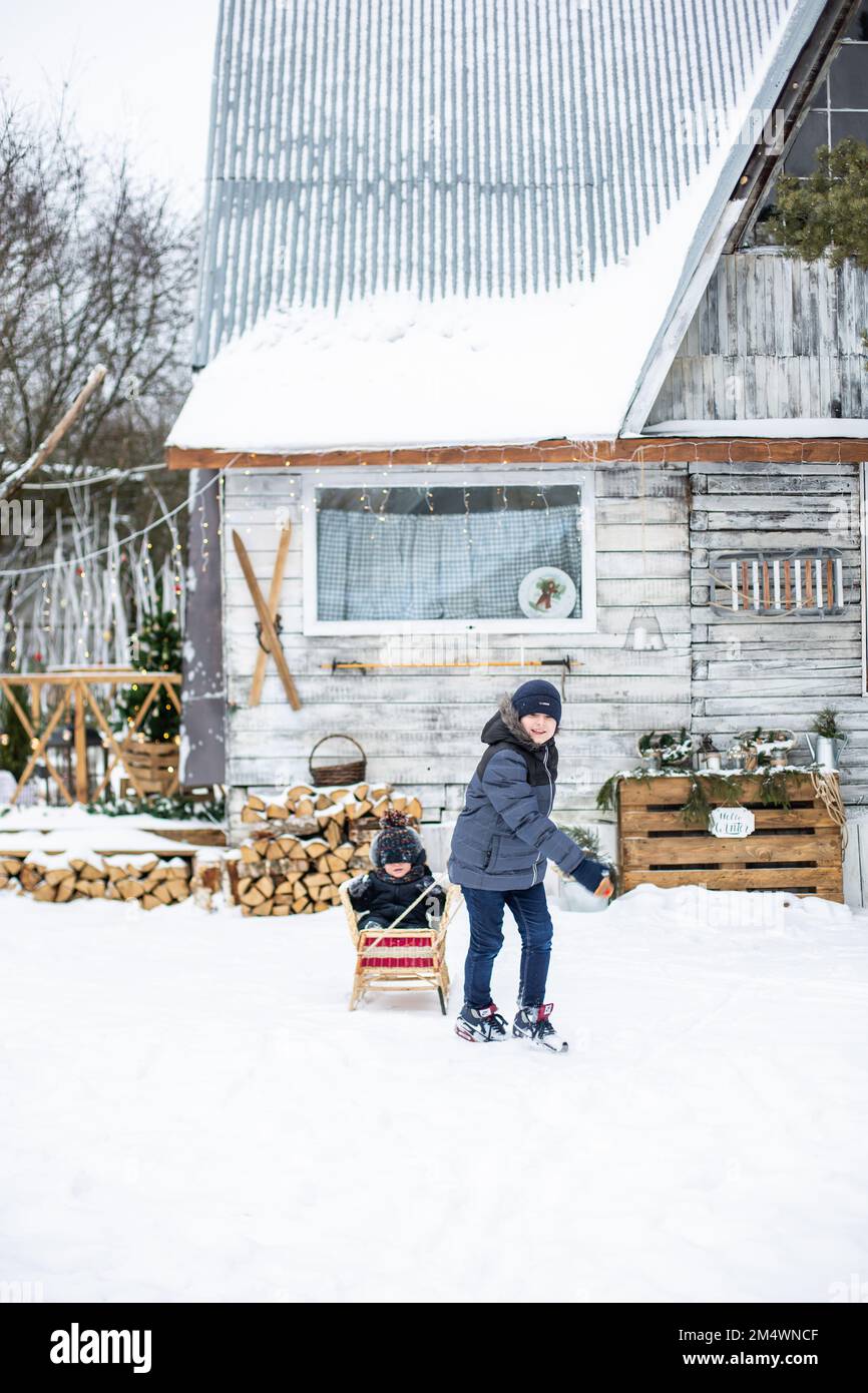 Boy pulling his friend on a sledge Stock Photo - Alamy